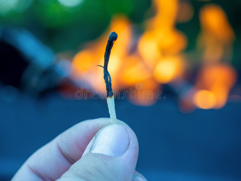 Close-up of a Man`s Hand Holding a Burnt Match. a Fire is Burning in ...