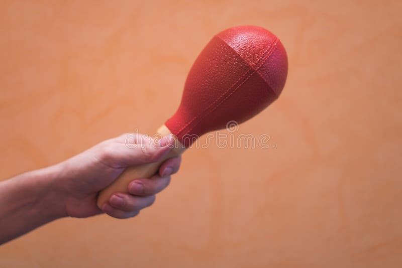 Close-up of a Man`s Hand Holding a Red Maraca on an Orange Backg Stock ...