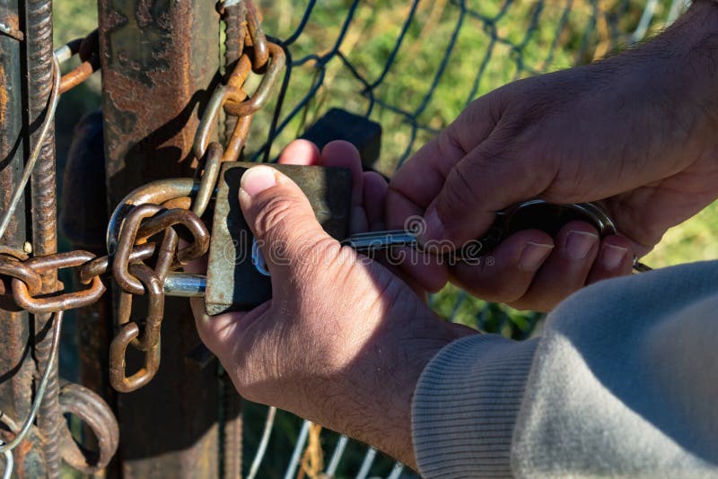 Close-up of a Man S Hands Opening the Lock in the Gate Stock Photo ...