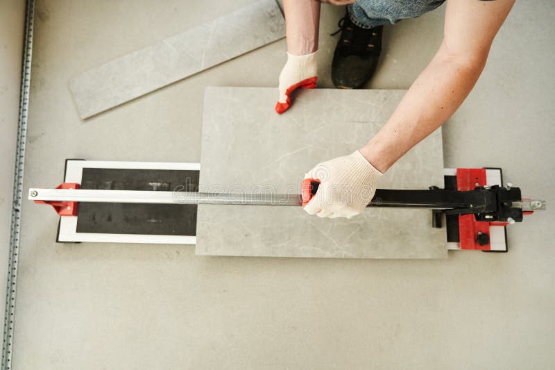 Close-up of the Master Cutting the Tile into Two Parts with a Machine ...