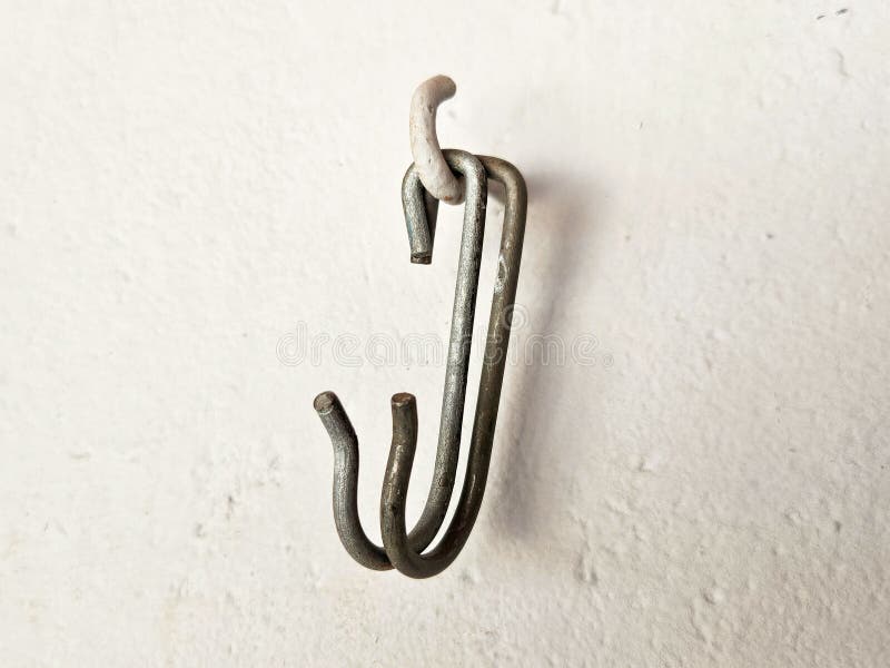 A Close-up of a Metal Hook Screwed into a Wall. the Hook is Curved at the End, Suggesting it is ...