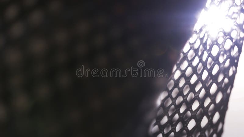 Close Up of an Object Surrounded by Mesh Black Material Against Bright Light. Action. Unusual ...