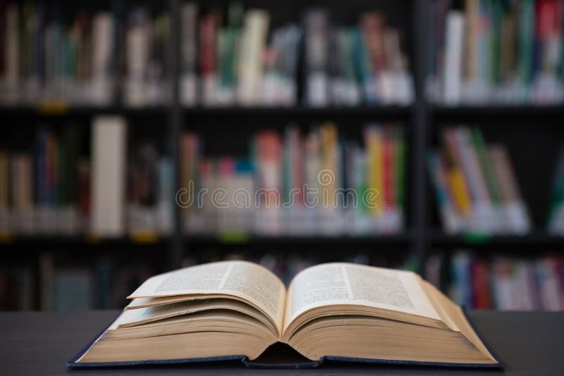Close Up of Open Book on Table Against Shelf Stock Photo - Image of ...