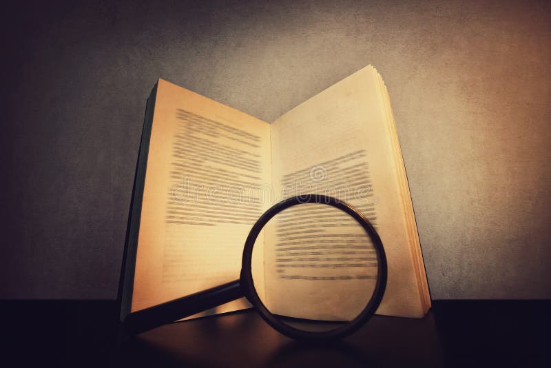Close Up of a Open Book on the Table and a Magnifying Glass Searching ...