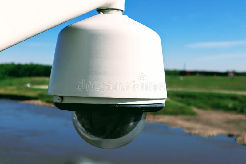 Close-up of a Outdoor Surveillance Camera. River and Field in the ...