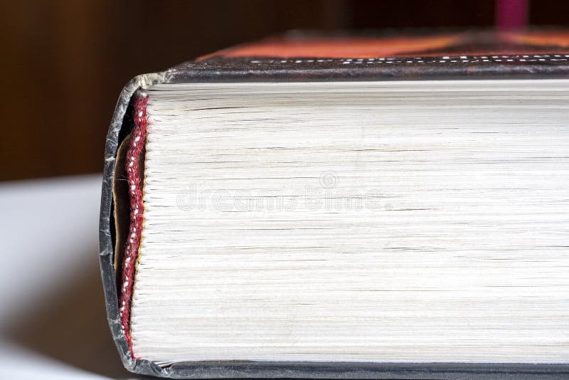 Close-up of a Part of a Thick and Heavy Book on a White Surface the ...