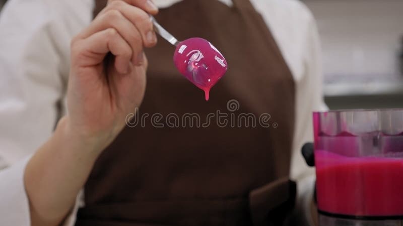 A Close-up of a Pastry Chef Holding a Spoon with Pink Icing for a ...