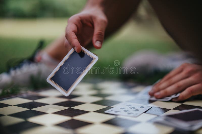 Close-up of Person Playing Card Game Outdoors on Checkerboard Stock ...