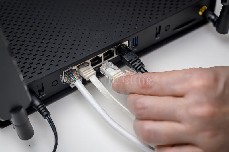A Close Up of a Person Plugging Wires into a Router. a Person Connects ...