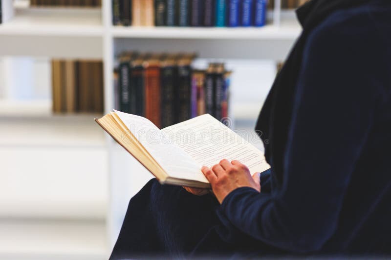 Close-up of Person Reading a Book in the Library. Studying in the ...
