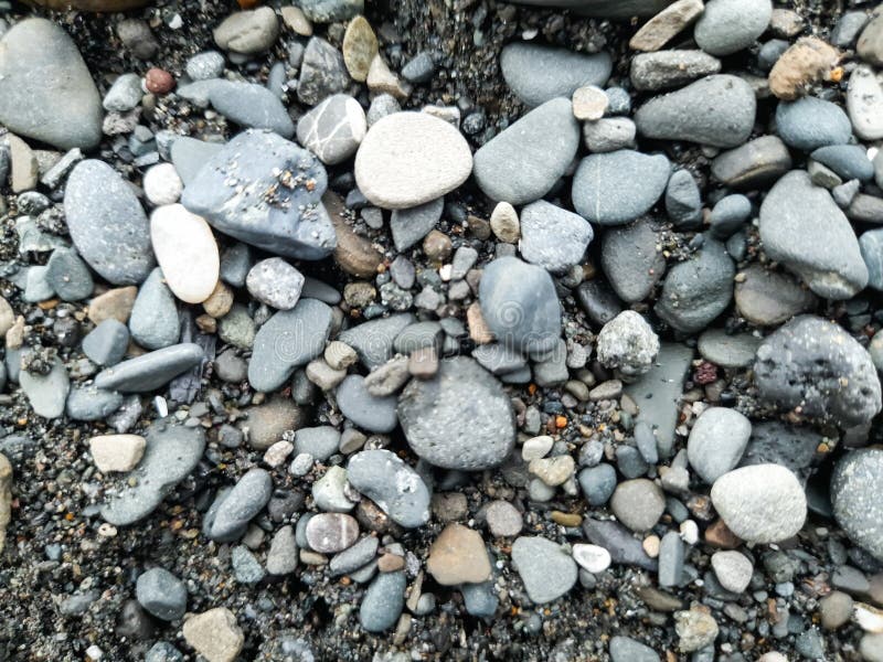 Close Up Pile of Smooth Small Stones on Black Sand Stock Photo - Image ...