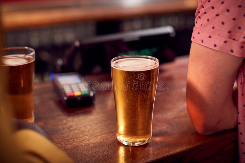 Close Up of Pints of Beer Standing on Counter of Bar with Customer ...