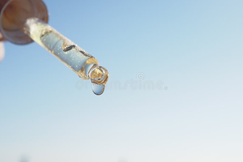 Close-up of a Pipette Dropping Liquid Against a Blue Background Stock ...