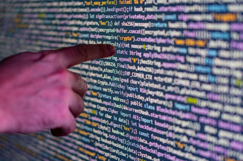 Close-up of a Pointing Hand Over a Large, Glowing Display Screen Filled with Colorful Code ...