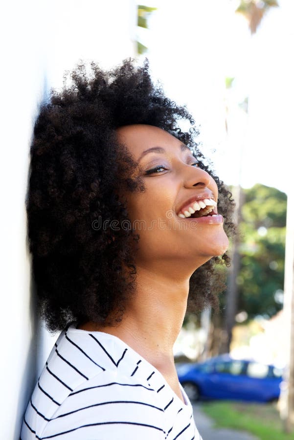 Close Up Cheerful Young African Woman With Hand In Hair And Laughing