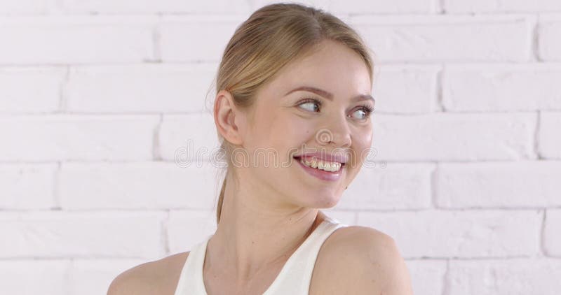 Portrait Of Beautiful Smiling Woman Standing On White Brick Wall She