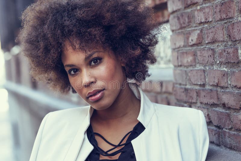 Young Black Woman With Afro Hairstyle Standing In Urban Background