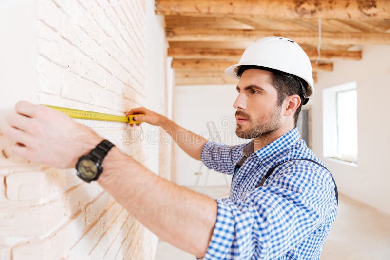 Close-up Portrait of Builder Measuring Wall Using Yellow Type Stock ...