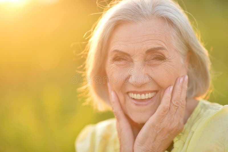 Close Up Portrait Of Happy Older Woman Standing Outside In Summer Stock