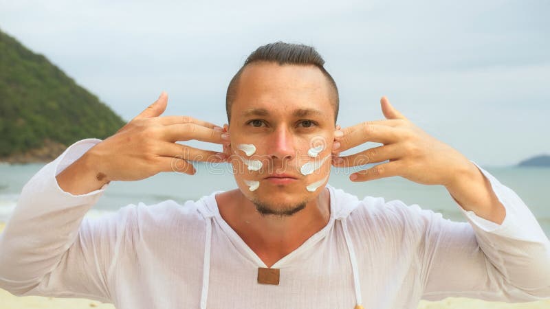Close-up Portrait Man Apply Sun Cream Protection Lotion, Looking at ... Close-up Portrait Man Apply Sun Cream Protection Lotion, Looking at ...