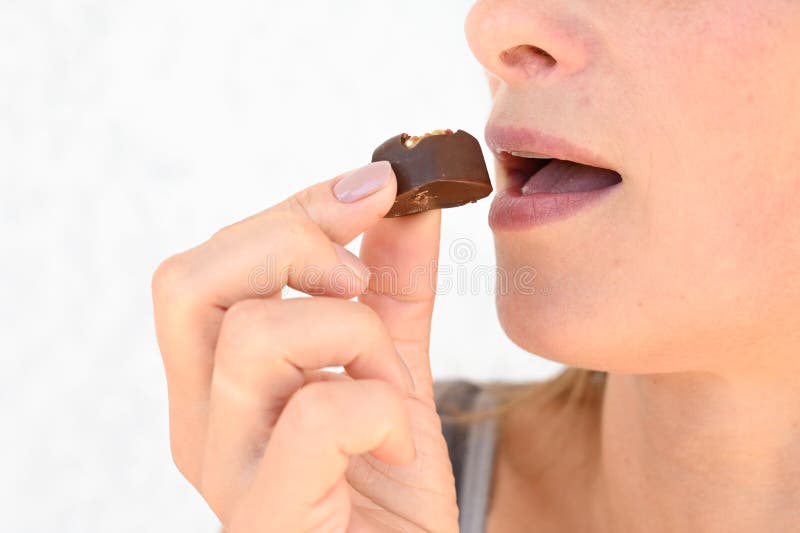 Close Up Portrait of Woman Biting a Chocolate Candy on Light Backround ...