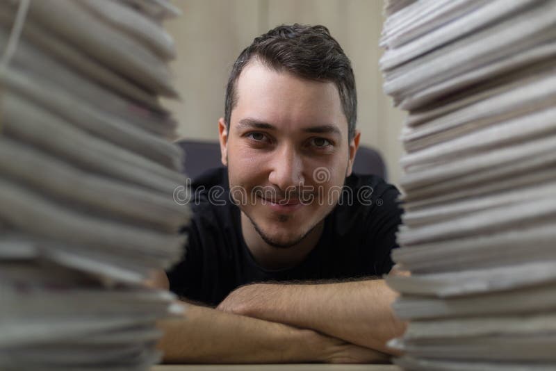 Close Up Portrait of a Young Journalist and a Stacks of Newspapers in ...