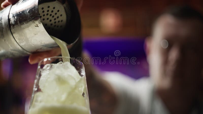 Close-up of Pouring a Cocktail from a Shaker into a Glass with Ice ...