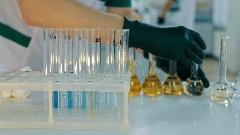 Close-up of Pouring a Yellow Chemical Solution into Test Tubes. Work in ...