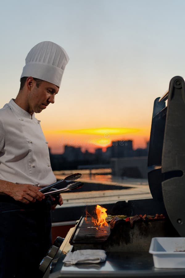 Close-up of a Professional Chef Cooking Bbq on a Rooftop at Sunset ...