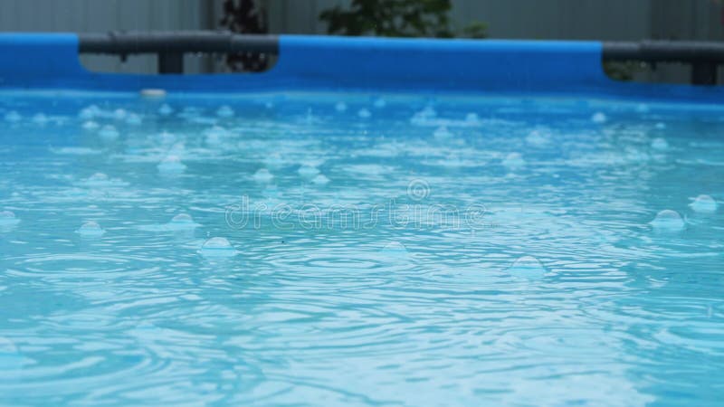 A Close-up of Raindrops Falling into a Blue Pool in Slow Motion ...