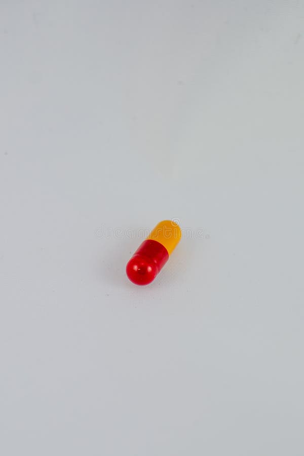 A Close Up of a Red and Yellow Pill in Front of a White Background ...