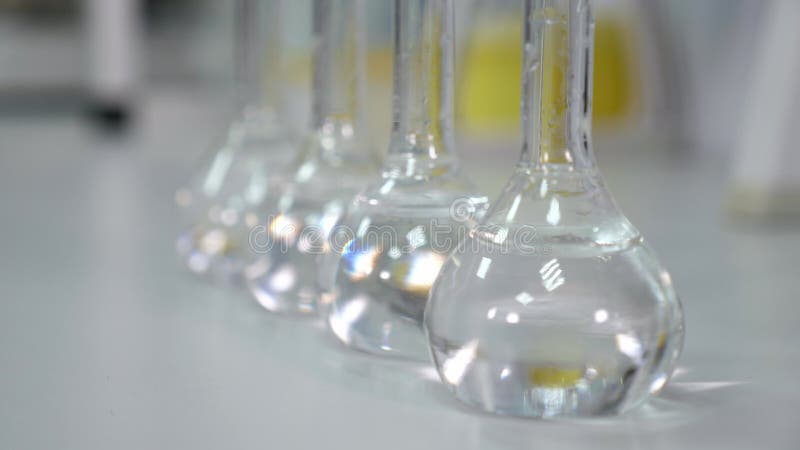 A Close-up of a Row of Glass Flasks with a Transparent Liquid in the ...