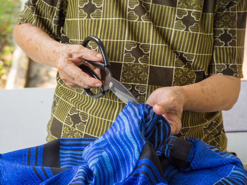 Close-up of Senior Woman Hands Using a Cutting Cloth with Scissors ...