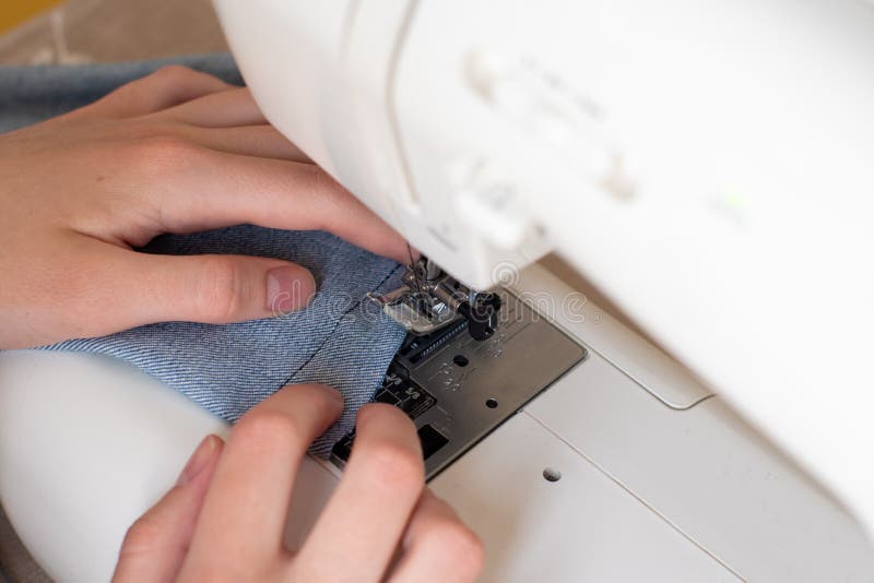 Close-up of Sewing on a Sewing Machine, Hands Guide the Fabric. the ...