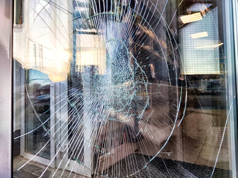 A Close-up of a Shattered Glass Door Window with a Spiderweb Pattern of ...