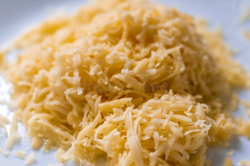 Close Up of Grated Cheddar Cheese Falling and Piling Up on White ...