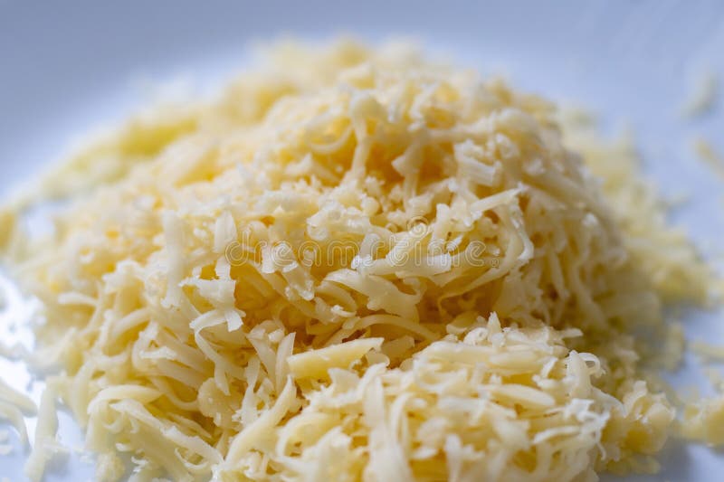 Close Up of Grated Cheddar Cheese Falling and Piling Up on White ...