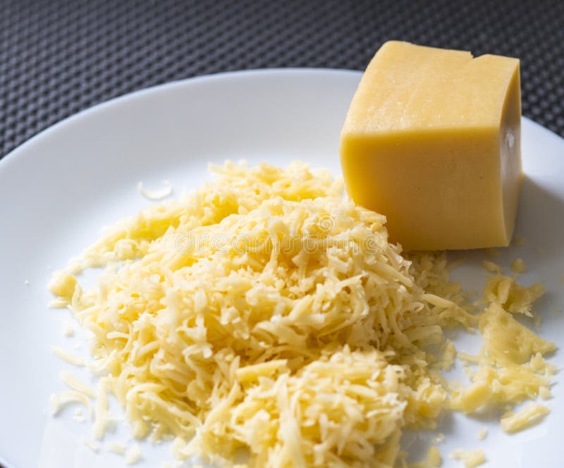 Close Up of Grated Cheddar Cheese Falling and Piling Up on White ...