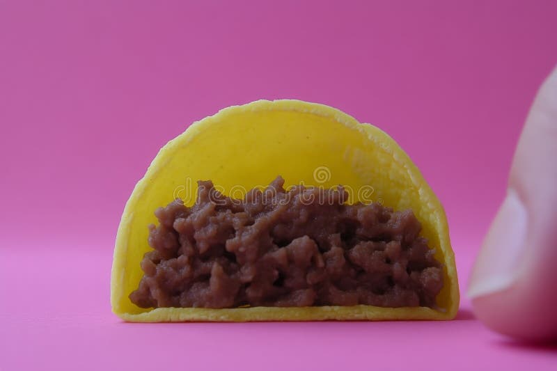 A Close-up Shot of a Hand Gripping a Fresh Taco with a Pink Backdrop ...