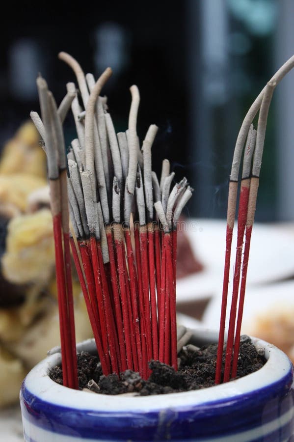 Close-up Shot of the Red Incense Sticks Putting in a White-blue Ceramic ...