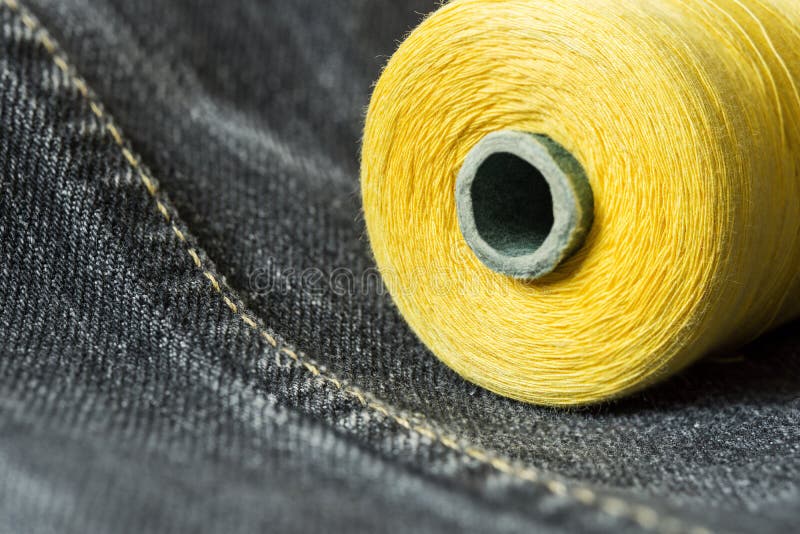 Close-up Shot of a Spool of Yellow Thread on Dark Grey Denim. Stock ...