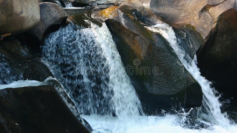 Close-up Shot of a Stream of Water Cascading Over a Dark, Rocky ...