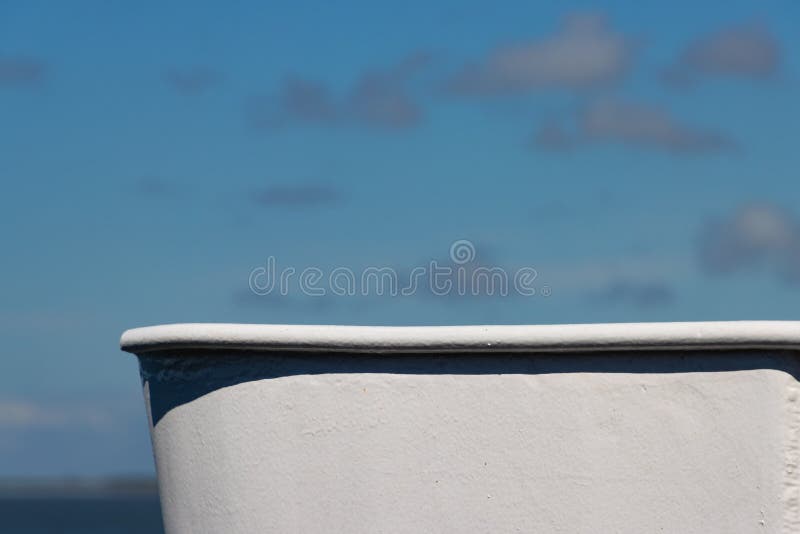 Close Up Side View of Bow of a White Ship Hull Against Blue Sky with ...
