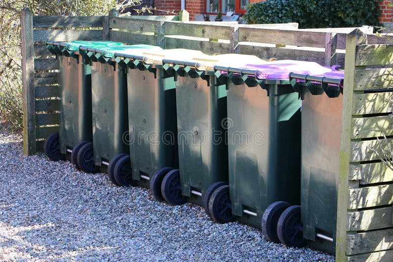 Close Up of Six Closed Garbage Bins with Different Colored Lids Stand ...