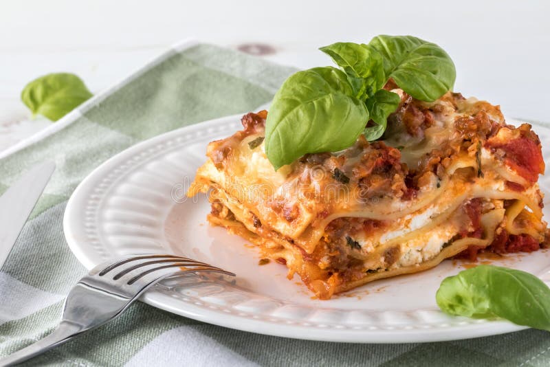 A Close Up of a Slice of Lasagna on a Plate Garnished with Basil. Stock ...