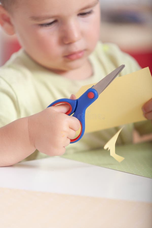 Close-up of a Small Child Cutting Out a Sheet of Paper with Scissors ...