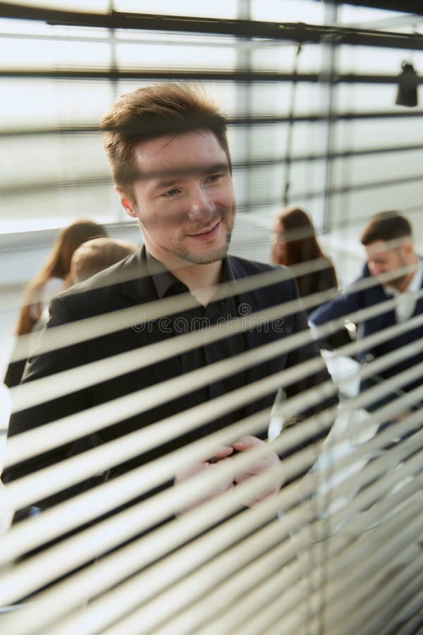 Close Up. Smiling Employee Looking through Office Blinds Stock Photo ...
