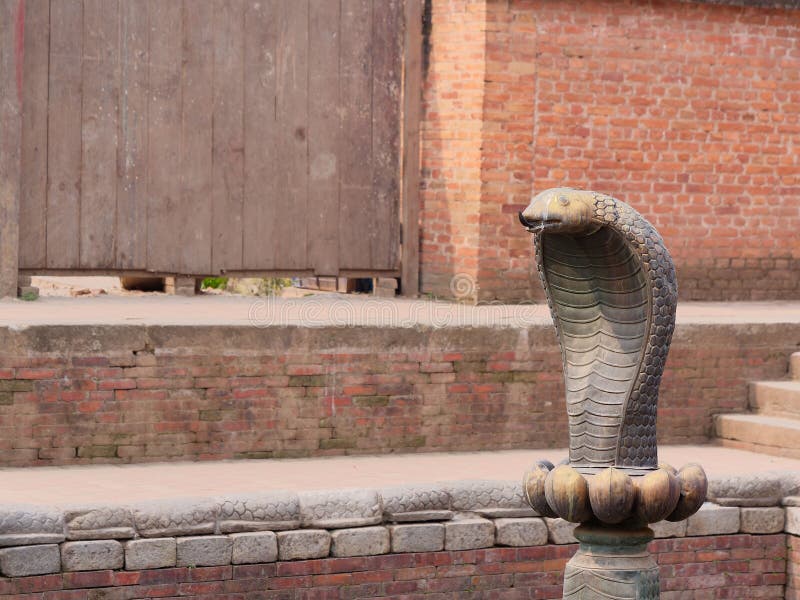 A Close-up of a Snake Statue in Front of a Rustic Brick Wall and Wooden ...