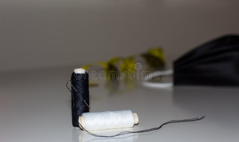 Close-up of Spools of Black and White Thread, a Needle, with a Mask on ...