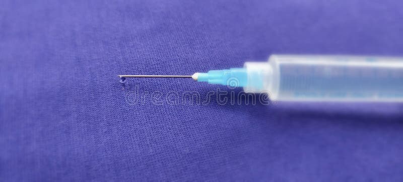 Close-up of a Syringe with Cannula and Drop in Front of Dark Blue ...